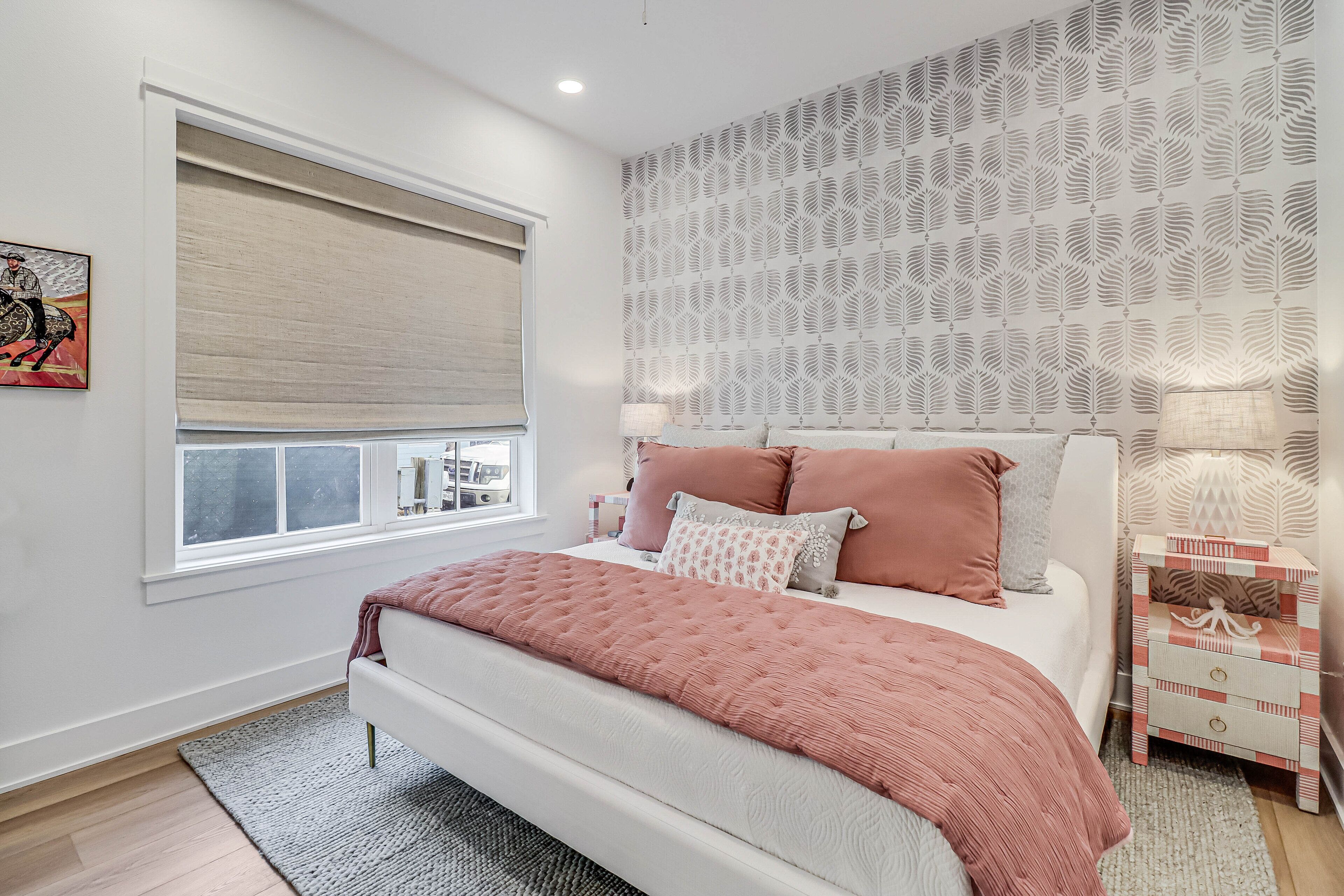 Quarto com cama, janela com cortina, parede estampada e mesa de cabeceira com abajur.