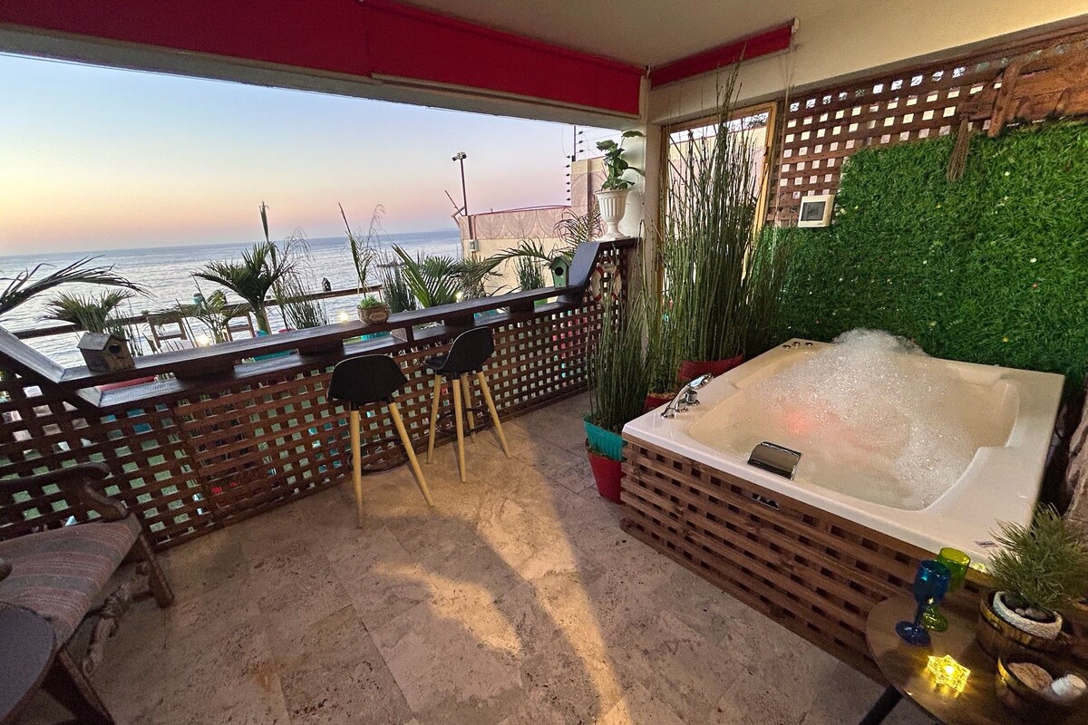 Varanda com vista para o mar, hidromassagem e área de estar ao ar livre.