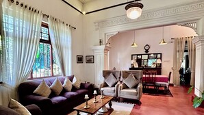 Sala de estar com tapete vermelho, um sofá marrom escuro e um sofá marrom claro com almofadas. Há uma mesa de centro de madeira com velas.