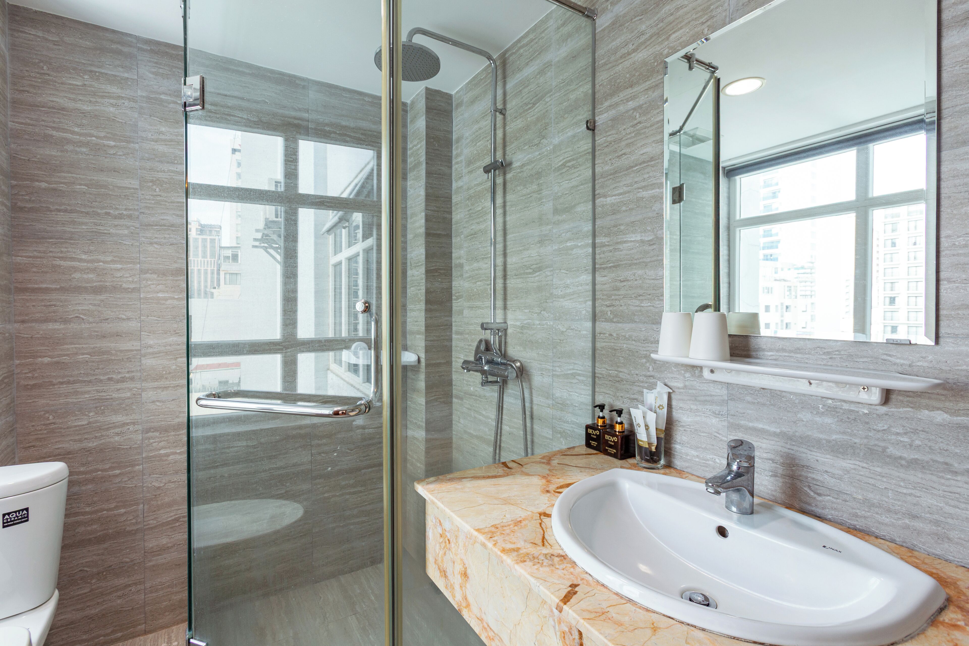 A modern bathroom with a glass-enclosed shower, a marble sink, and a large mirror.