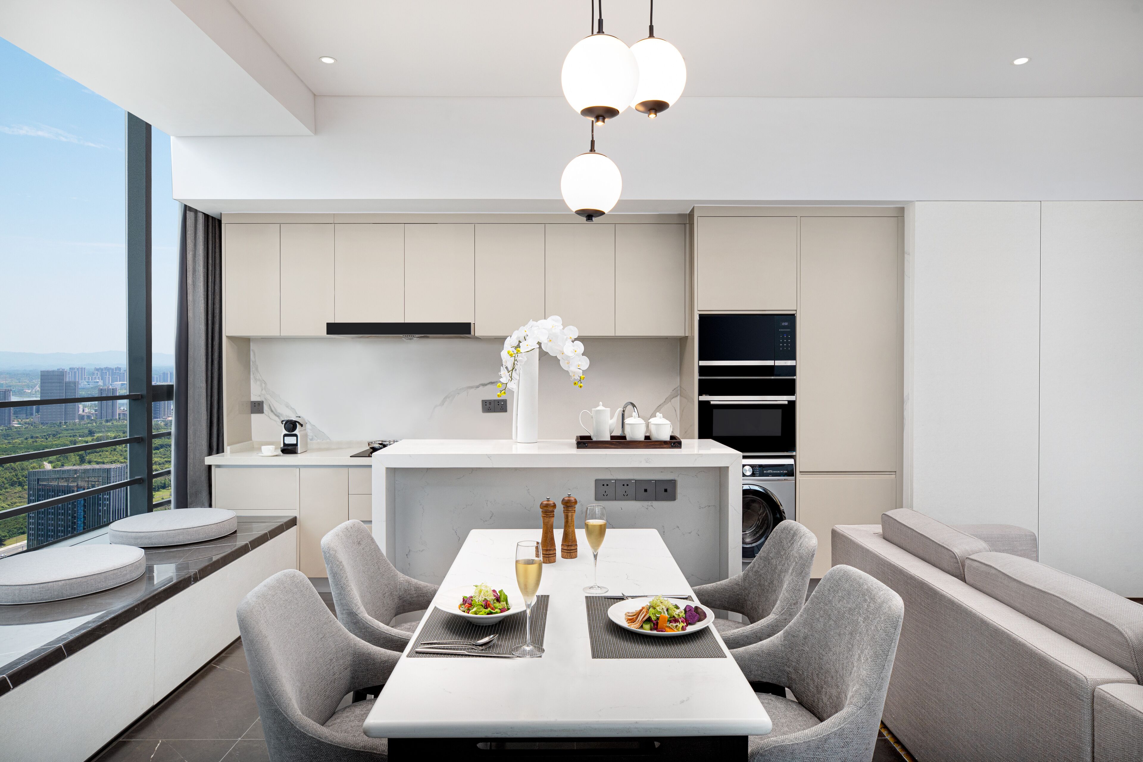 Cozinha moderna com área de refeições, grandes janelas e vista para a cidade.