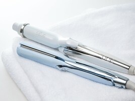 Dois aparelhos para alisar cabelo sobre uma toalha branca.