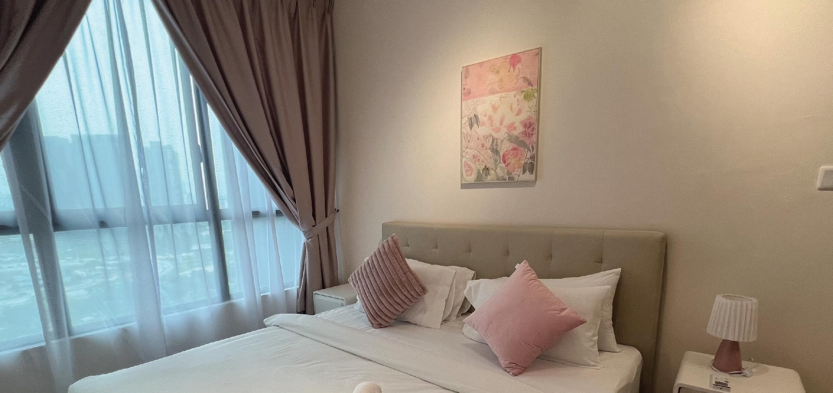 Quarto de hotel com uma cama, mesa de cabeceira, abajur e um quadro na parede.