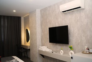 Casa de banho moderna com lavatório embutido, espelho, televisão de ecrã plano e porta-toalhas.