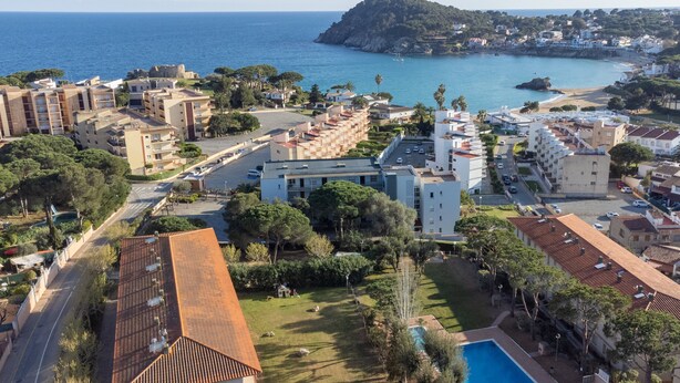 Uma área residencial à beira-mar, com piscina, vários edifícios e vista para o oceano.