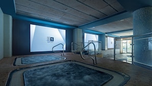 Uma área de spa com duas banheiras de hidromassagem, uma porta de vidro que dá para o exterior e uma placa indicando o local.