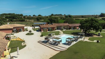Um resort com piscina, área de estar ao ar livre e um prédio grande com telhado telhado.