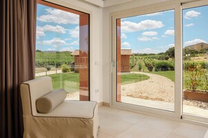 Quarto com uma grande porta de correr de vidro que dá para vista de um vinhedo.