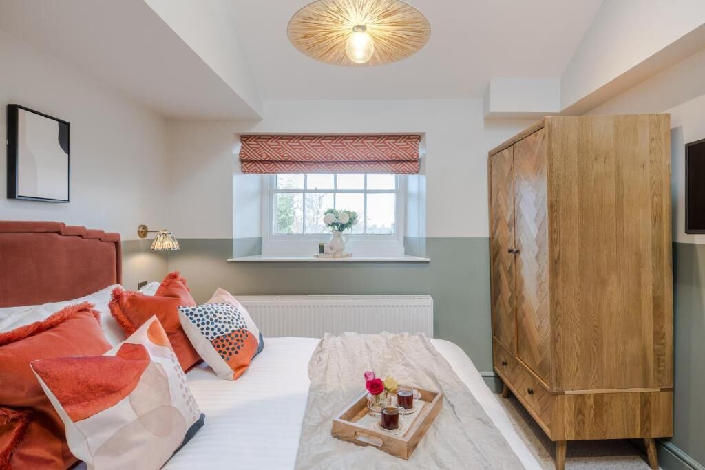Quarto com cama, guarda-roupa de madeira, janela com vista e mesa de cabeceira com bandeja.