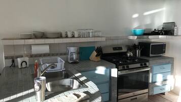 Uma cozinha com pia, fogão, micro-ondas e diversos utensílios.