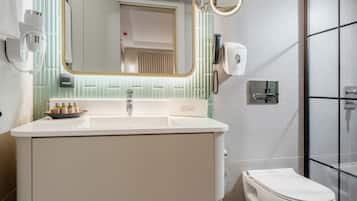 Uma casa de banho moderna com toucador branco, um espelho grande, cabine de duche em vidro e sanita.