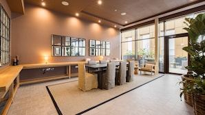 Uma área de estar interna moderna, com um balcão comprido, cadeiras estofadas e grandes janelas que oferecem luz natural.