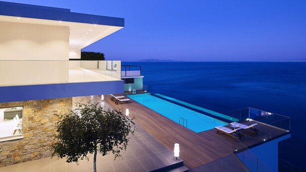 Um edifício moderno com piscina, vista para o mar e área de refeições.