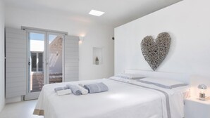 Quarto com uma cama grande, decoração em formato de coração na parede e porta de vidro deslizante para área externa.