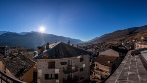 Uma aldeia montanhosa com edifícios tradicionais, céu claro e sol brilhante.