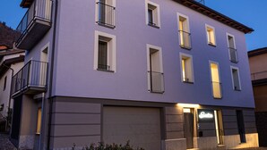 Um edifício com várias andares, varandas, garagem e entrada bem iluminada.