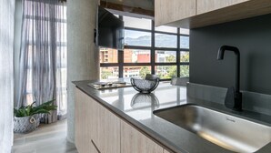 Cozinha moderna com uma janela grande, uma pia de aço inoxidável e uma torneira preta.