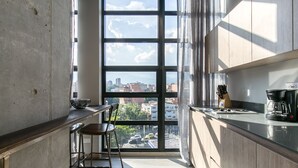 Cozinha moderna com uma janela grande, uma cafeteira e uma tigela no balcão.