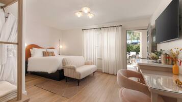 Quarto de hotel com cama, escrivaninha, cadeira e televisão.