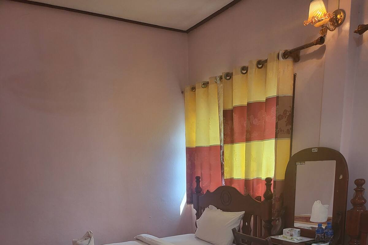 Quarto de hotel com duas camas, um cabeceiro de madeira, um espelho e uma mesa de cabeceira com abajur.