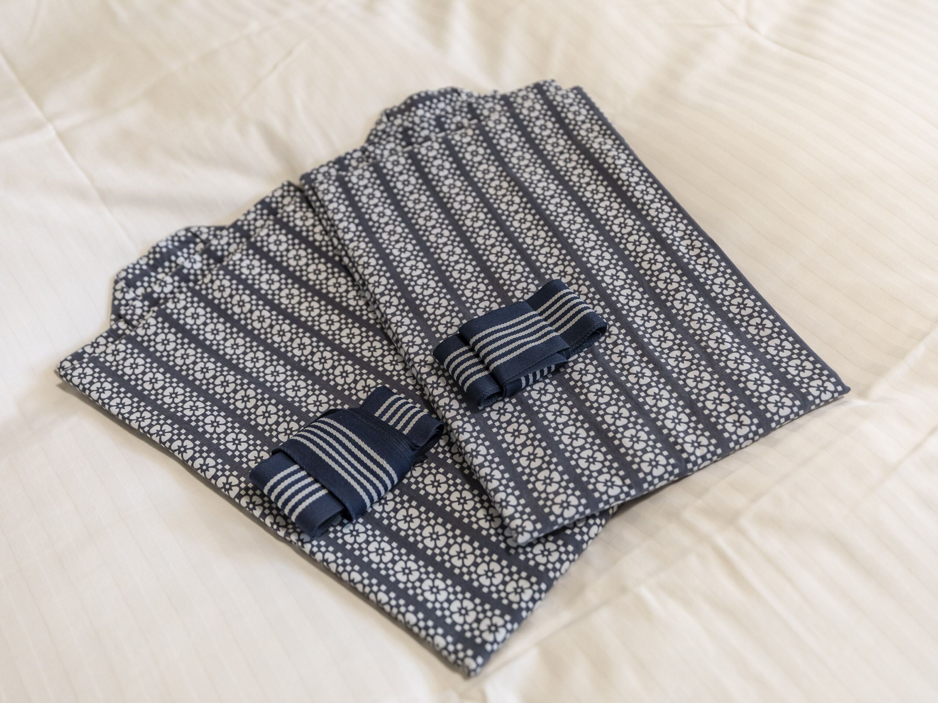 Uma peça de roupa bem dobrada com padrão floral e punhos listrados sobre um tecido texturizado.