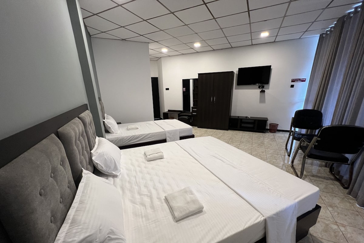 Quarto de hotel com duas camas, televisão, escrivaninha e uma cadeira.