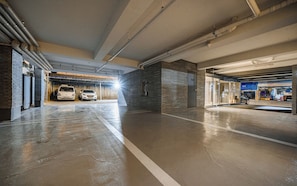 Garagem de estacionamento em vários níveis, com piso limpo e brilhante e dutos aparentes.