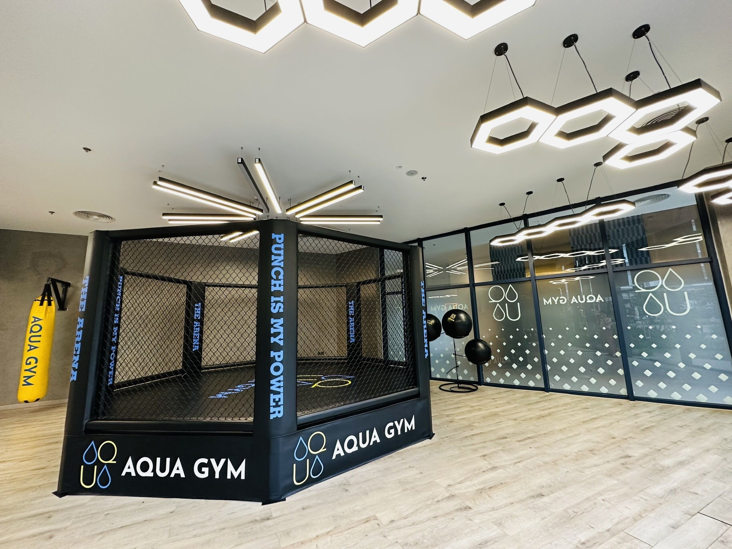 Uma academia com ringue de boxe, saco de pancadas e o logotipo de uma gota d'água na parede.