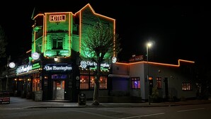 Um hotel com um letreiro grande escrito 'HOTEL', próximo a um bar esportivo e um pub.