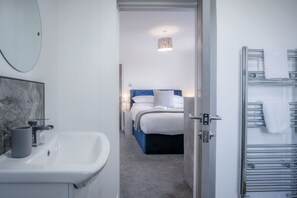 Uma casa de banho moderna com lavatório, espelho e porta-toalhas.