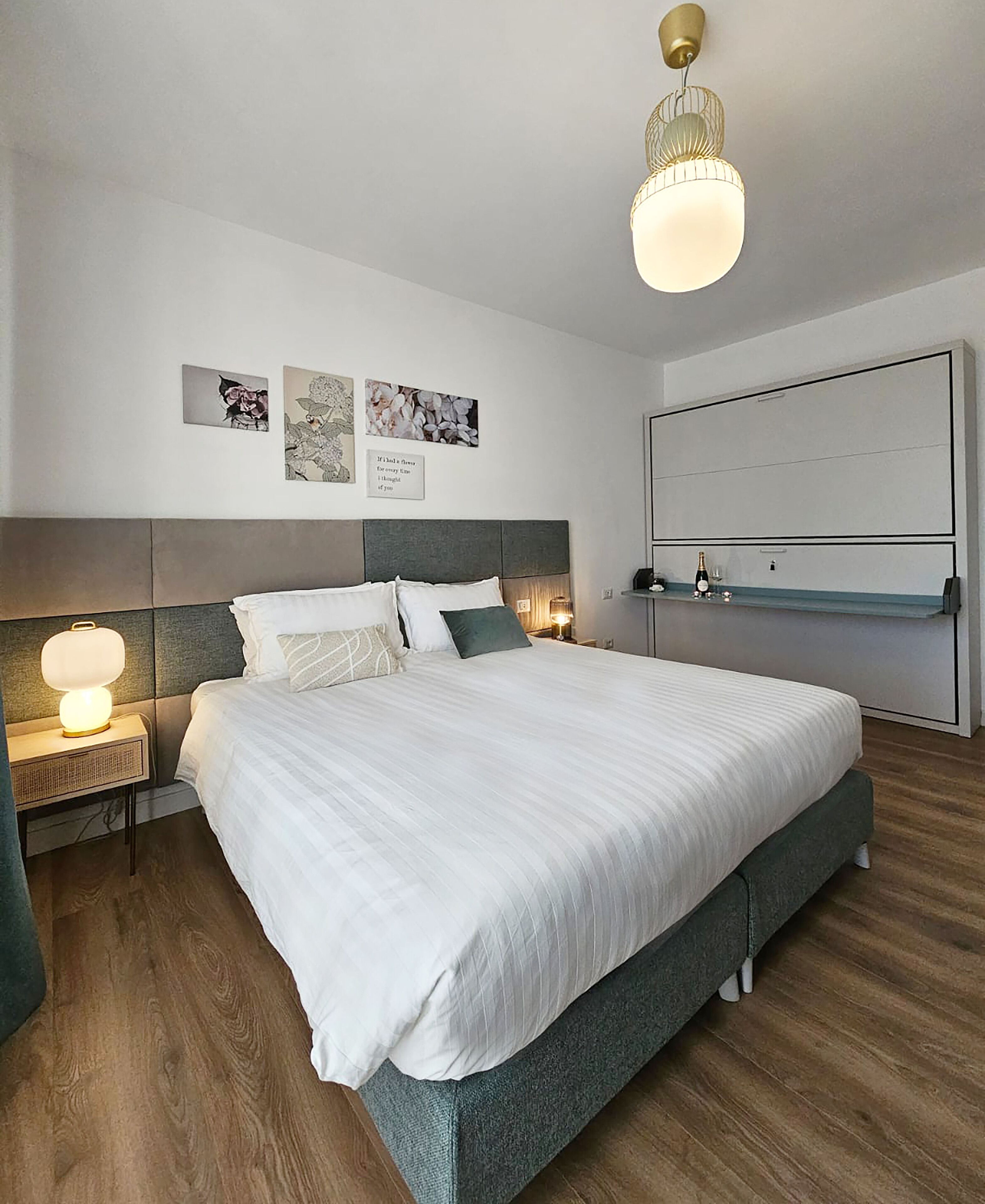 Quarto moderno com uma cama grande, abajures e quadros nas paredes.