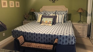 Quarto com uma cama, duas mesas de cabeceira, um relógio de parede e um objeto decorativo na parede.