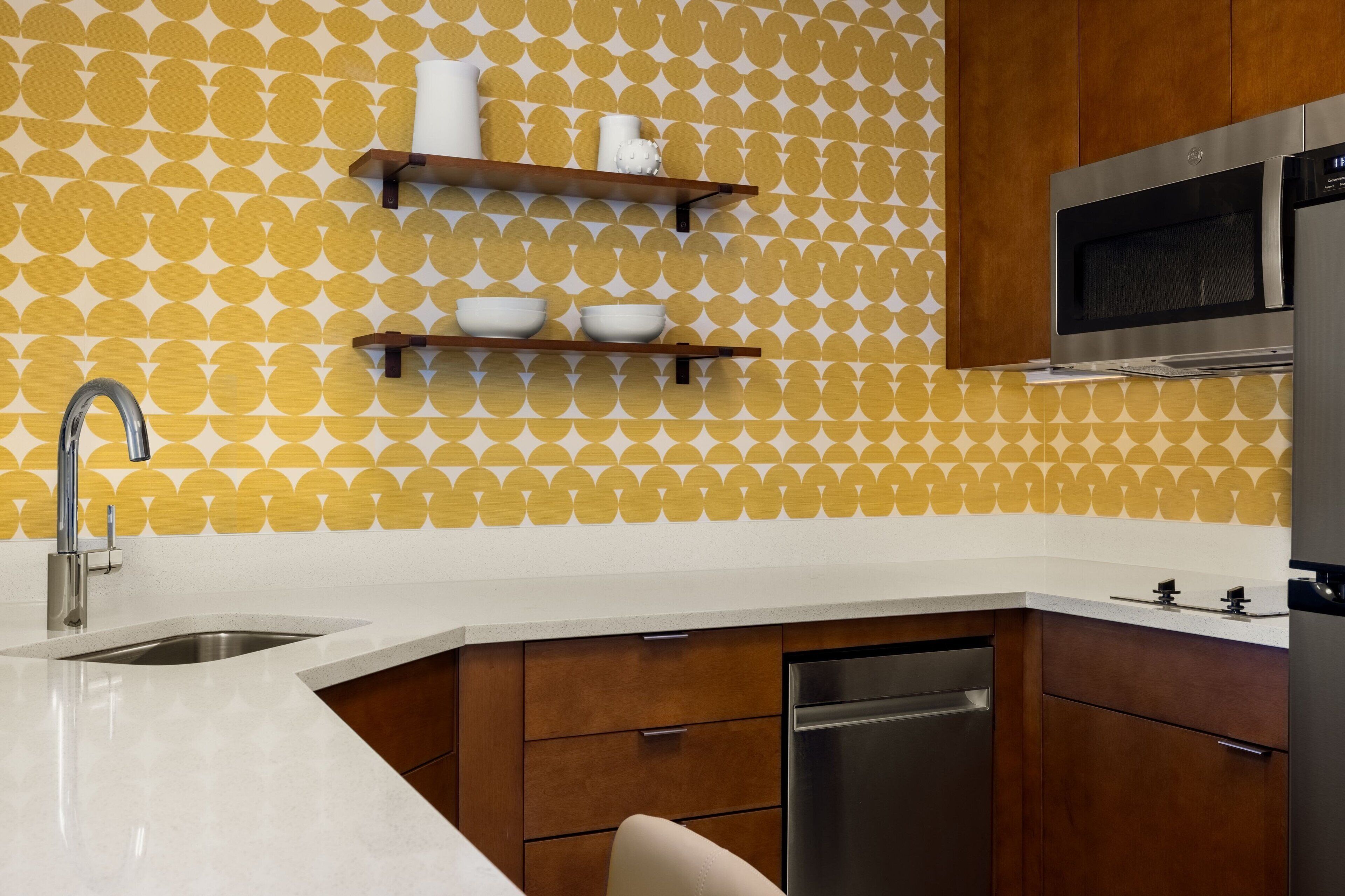 Uma cozinha moderna com painel de fundo geométrico, eletrodomésticos de aço inoxidável e armários de madeira.