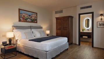 Quarto bem arrumado com cama, mesas de cabeceira, guarda-roupa, espelho e um quadro na parede.