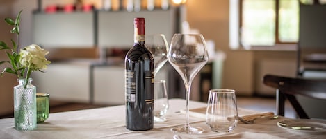 Mesa posta com uma garrafa de vinho, duas taças de vinho e um vaso com flores.