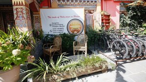 Um restaurante com um letreiro anunciando pizza italiana, mesas ao ar livre com cadeiras de vime e bicicletas estacionadas em frente.