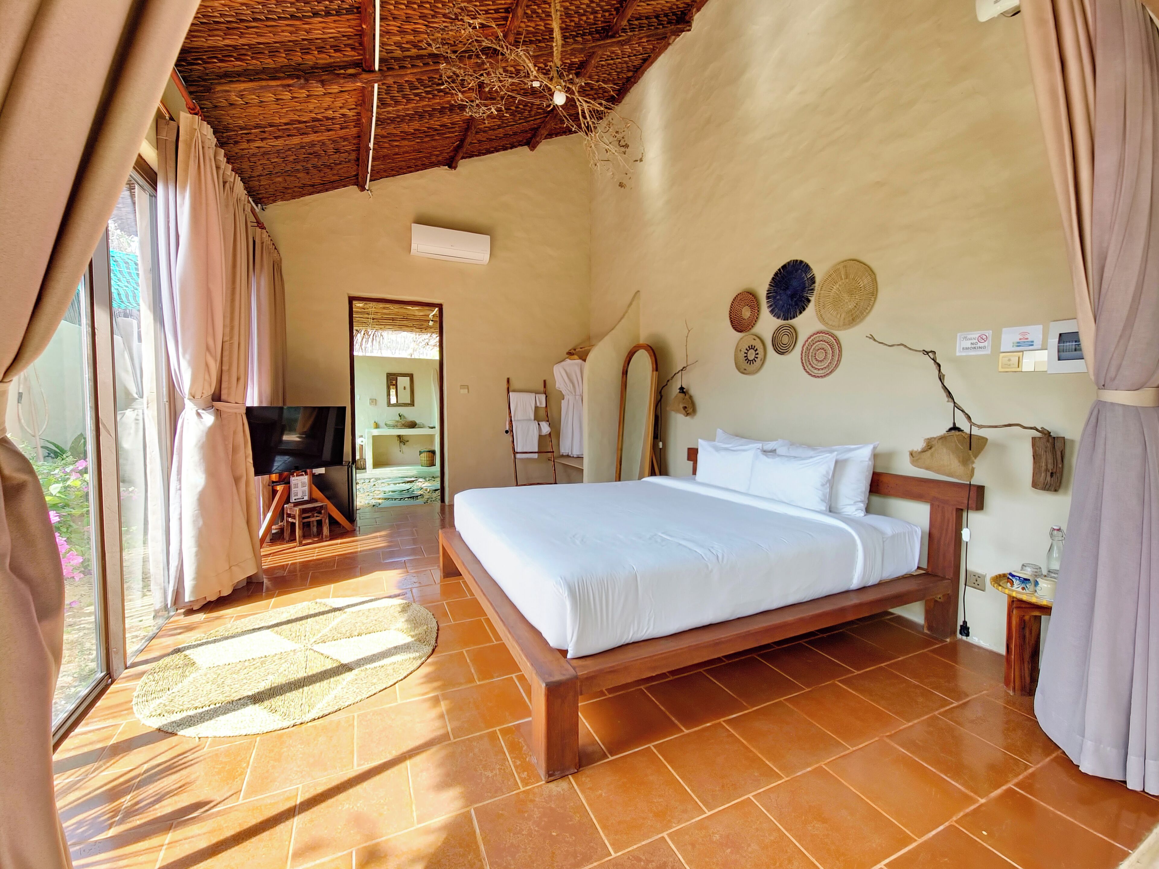 Quarto com uma cama grande, televisão e vista para o exterior.