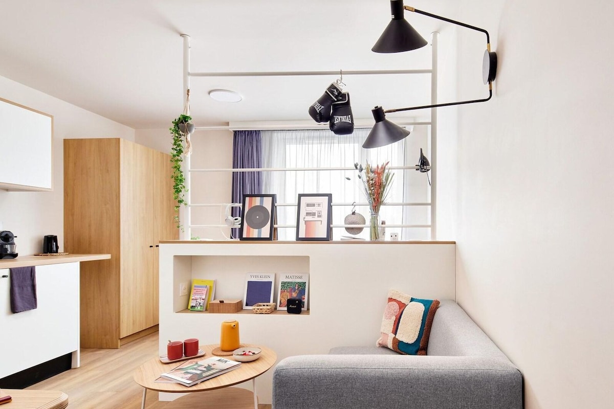 Um espaço de estar moderno e compacto com cozinha compacta, área de jantar e sala de estar com sofá e mesa pequena.