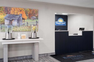 Uma área de recepção com balcão, uma pintura de uma cabana rústica e uma placa da Days Inn by Wyndham.