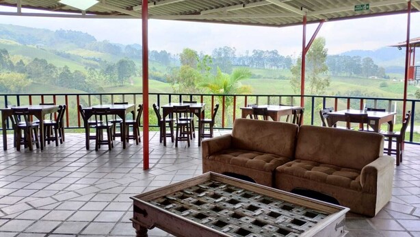 Uma área de estar coberta ao ar livre, com mesas, cadeiras, um sofá e uma mesa de centro.