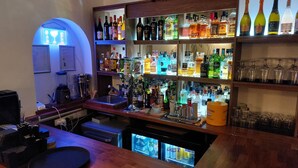 Uma área de bar com prateleiras cheias de garrafas de bebidas, uma pia e um refrigerador.
