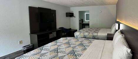 Quarto de hotel com duas camas, televisão, escrivaninha e espelho.