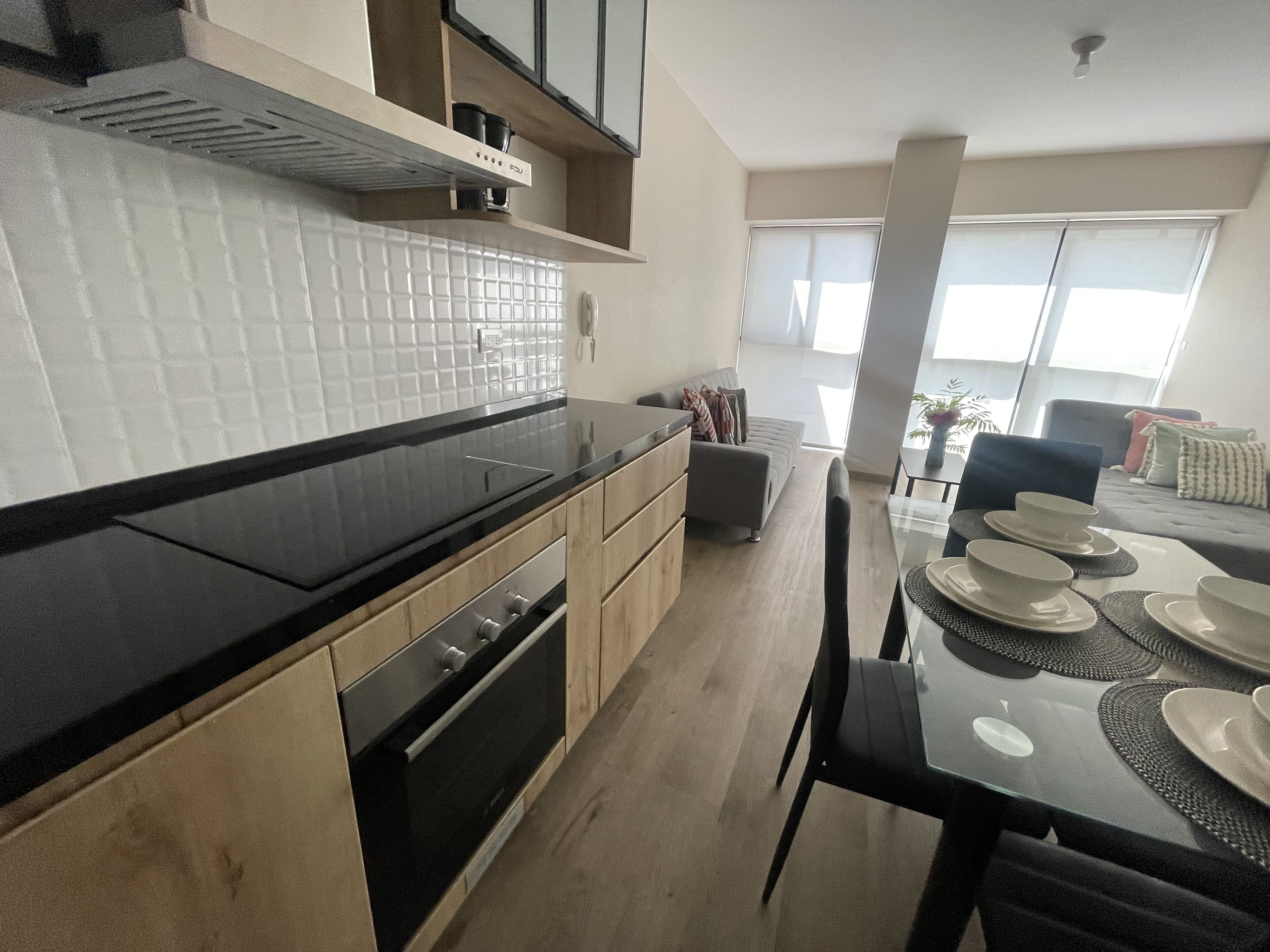 Uma cozinha moderna com bancada preta, armários de madeira e forno embutido.