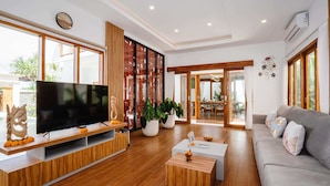 Uma sala de estar moderna com televisão de tela plana em um móvel de madeira, um sofá cinza e uma mesa de centro.