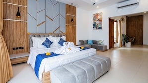 Quarto de hotel moderno com uma cama grande, um banco cinzento, uma parede de destaque em madeira e um quadro na parede.