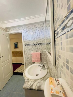 Uma casa de banho com uma pia branca, um espelho e um revestimento de azulejos.