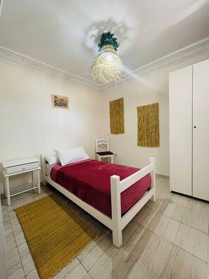Quarto com cama, mesa de cabeceira, guarda-roupa e luminária pendente.