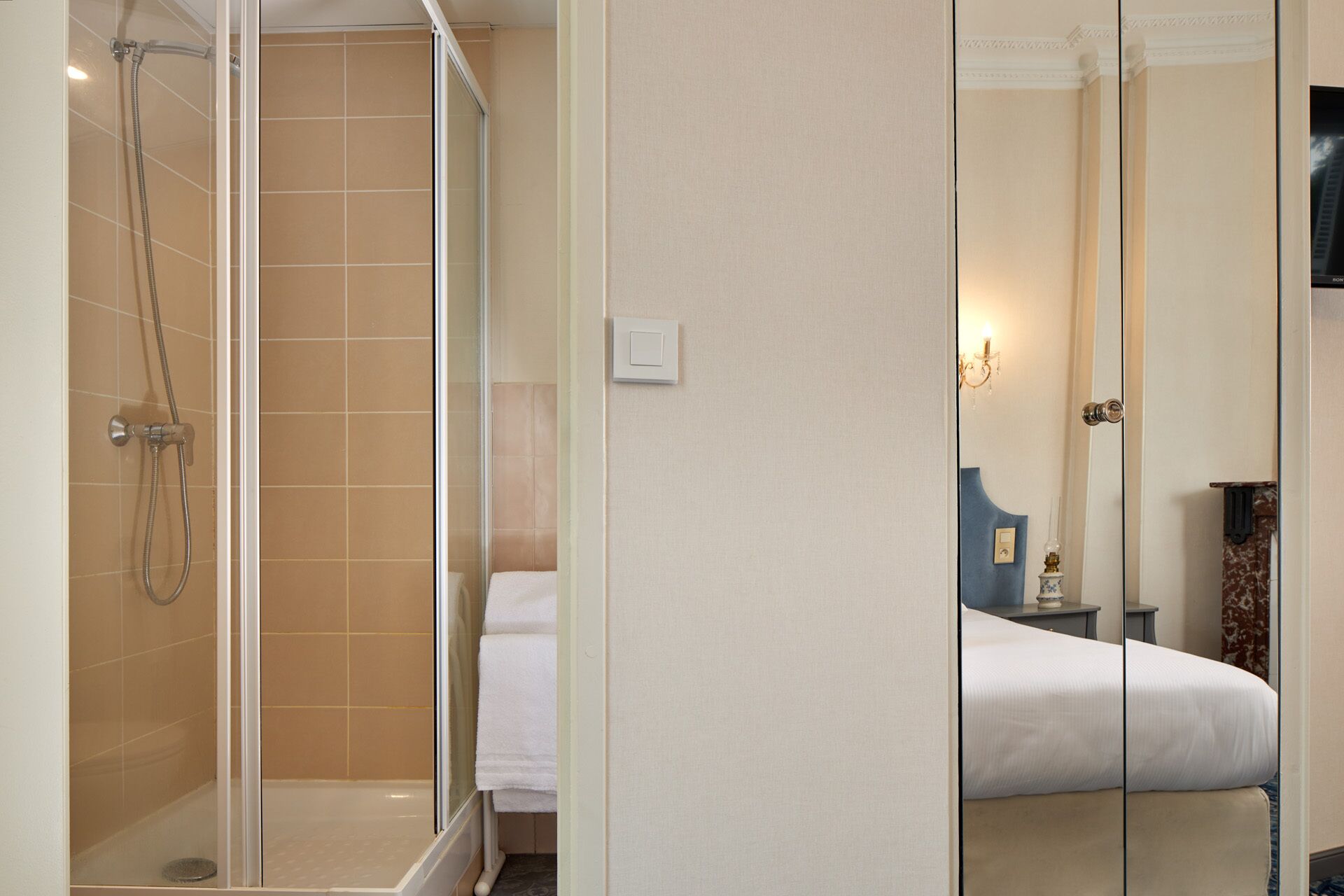 Casa de banho de hotel com chuveiro envidraçado, banheira branca e toalheiro visível.