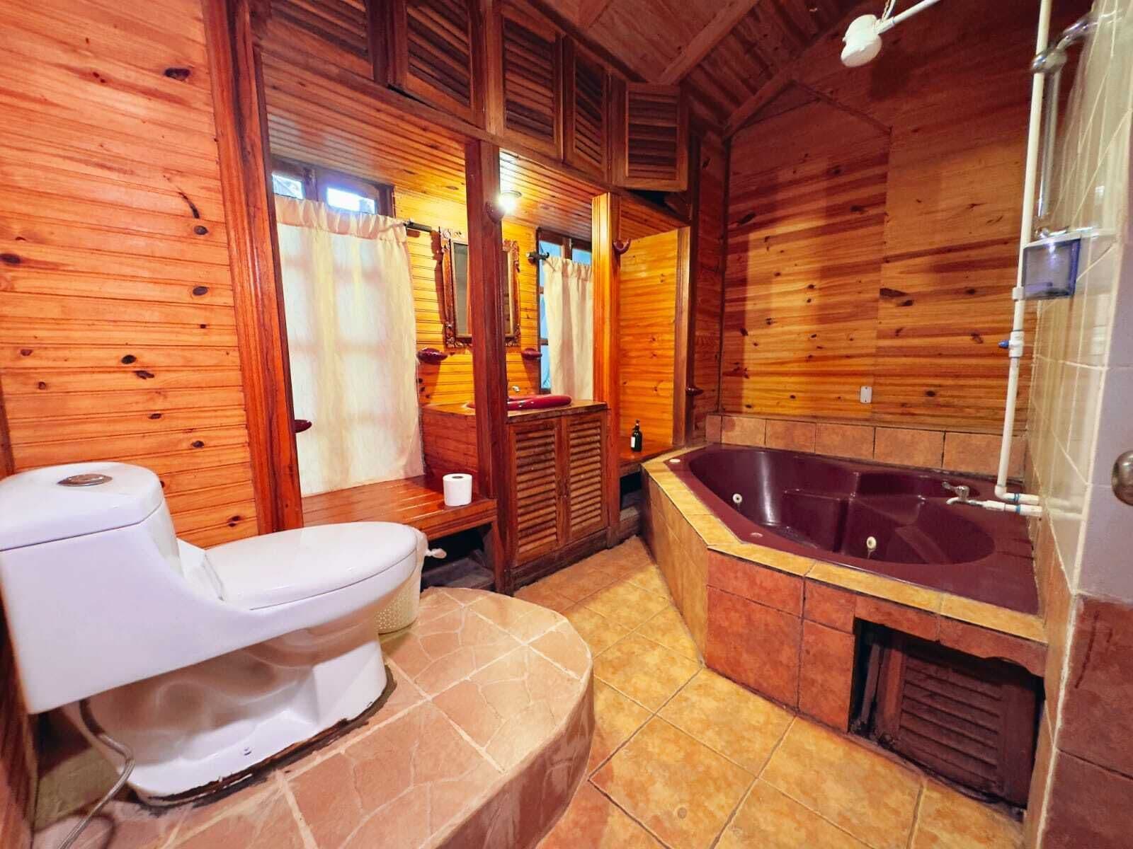 Casa de banho de uma cabana de madeira, com sanita, banheira e zona de duche.