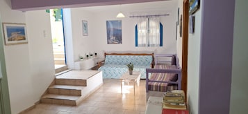 Quarto aconchegante com cama, uma pequena mesa e escada que dá acesso a outro espaço.
